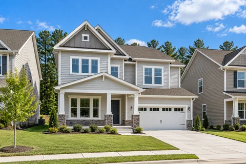 Two-story home with a front porch and a sunny lawn