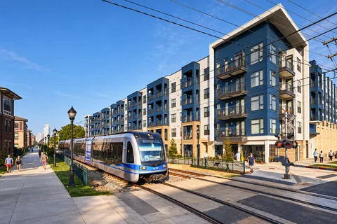 Light rail beside contemporary residences and a neighborhood walking path